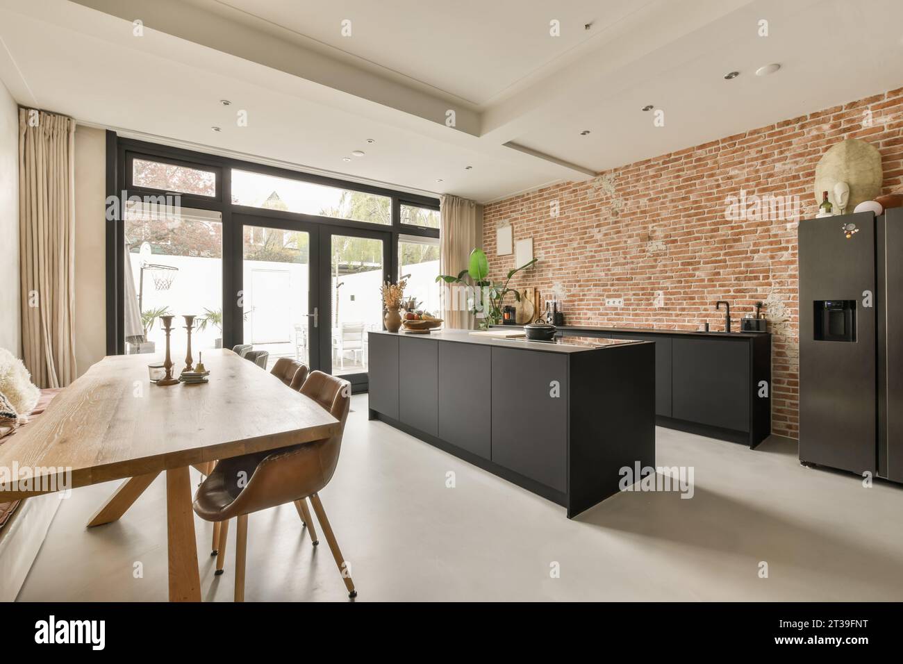 Wooden dining table with chairs arranged in front of open plan kitchen ...