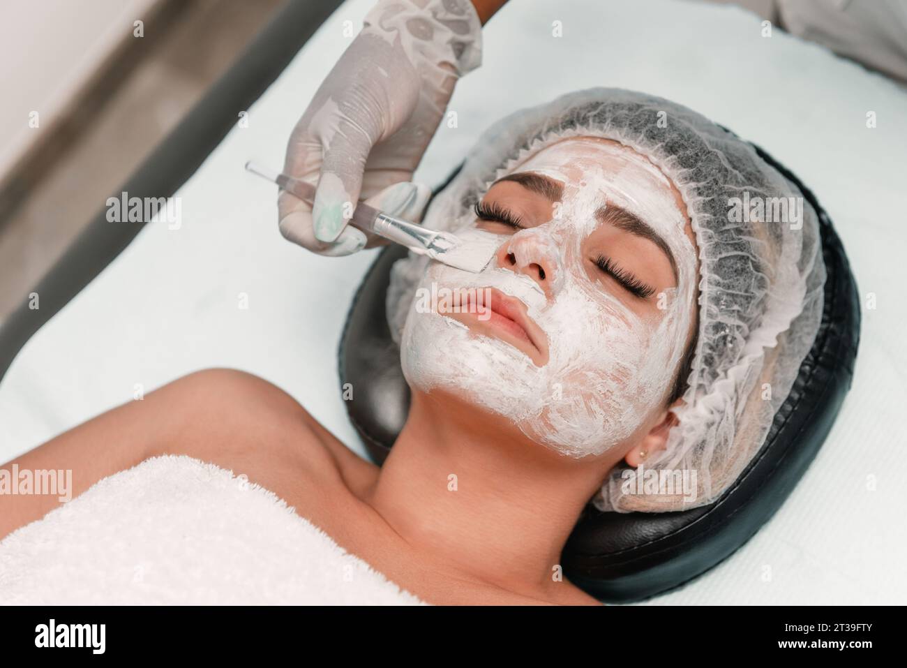 High angle of crop anonymous aesthetician applying moisturizing mask ...