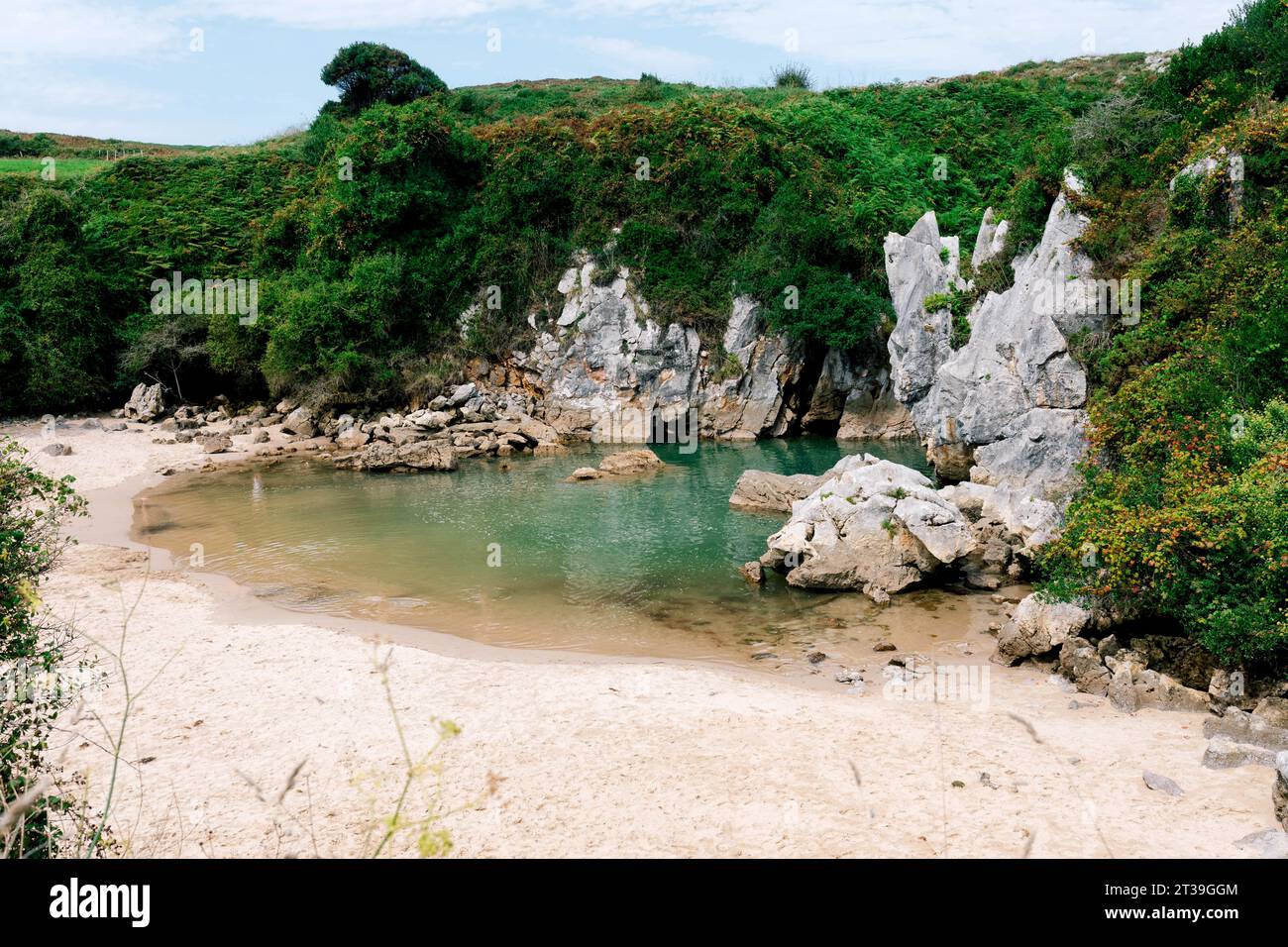 Serene hidden lagoon surrounded by rugged cliffs and lush greenery with ...