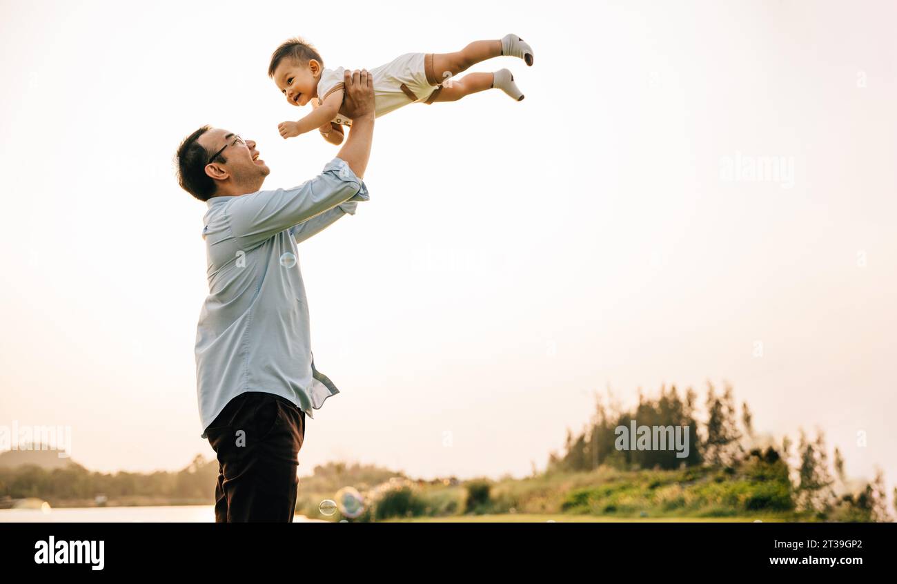 Father holds his baby daughter up high throwing up Stock Photo - Alamy