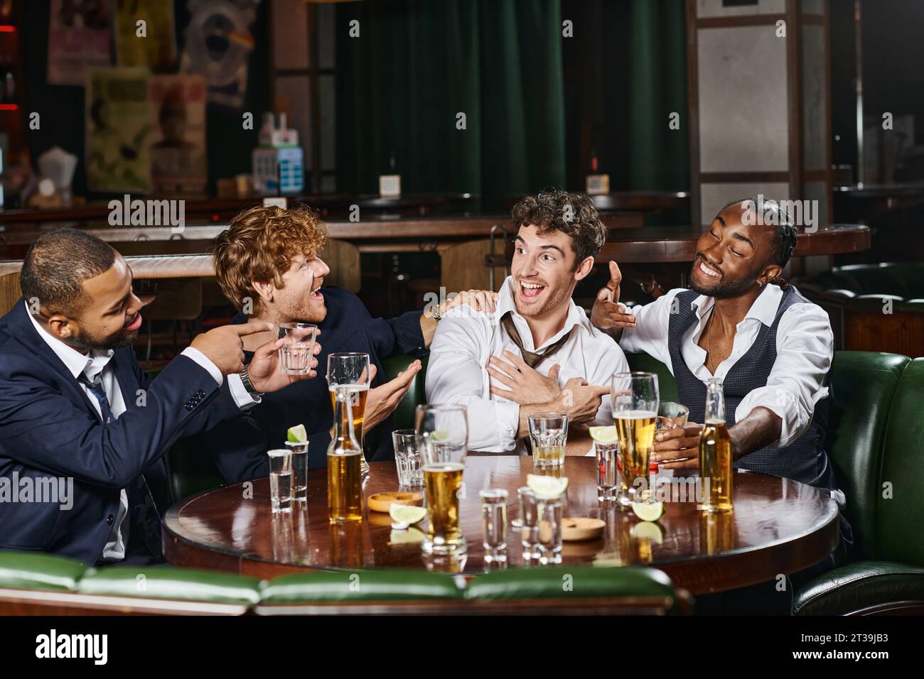 happy multiethnic men pointing at friend in bar, male friends during ...