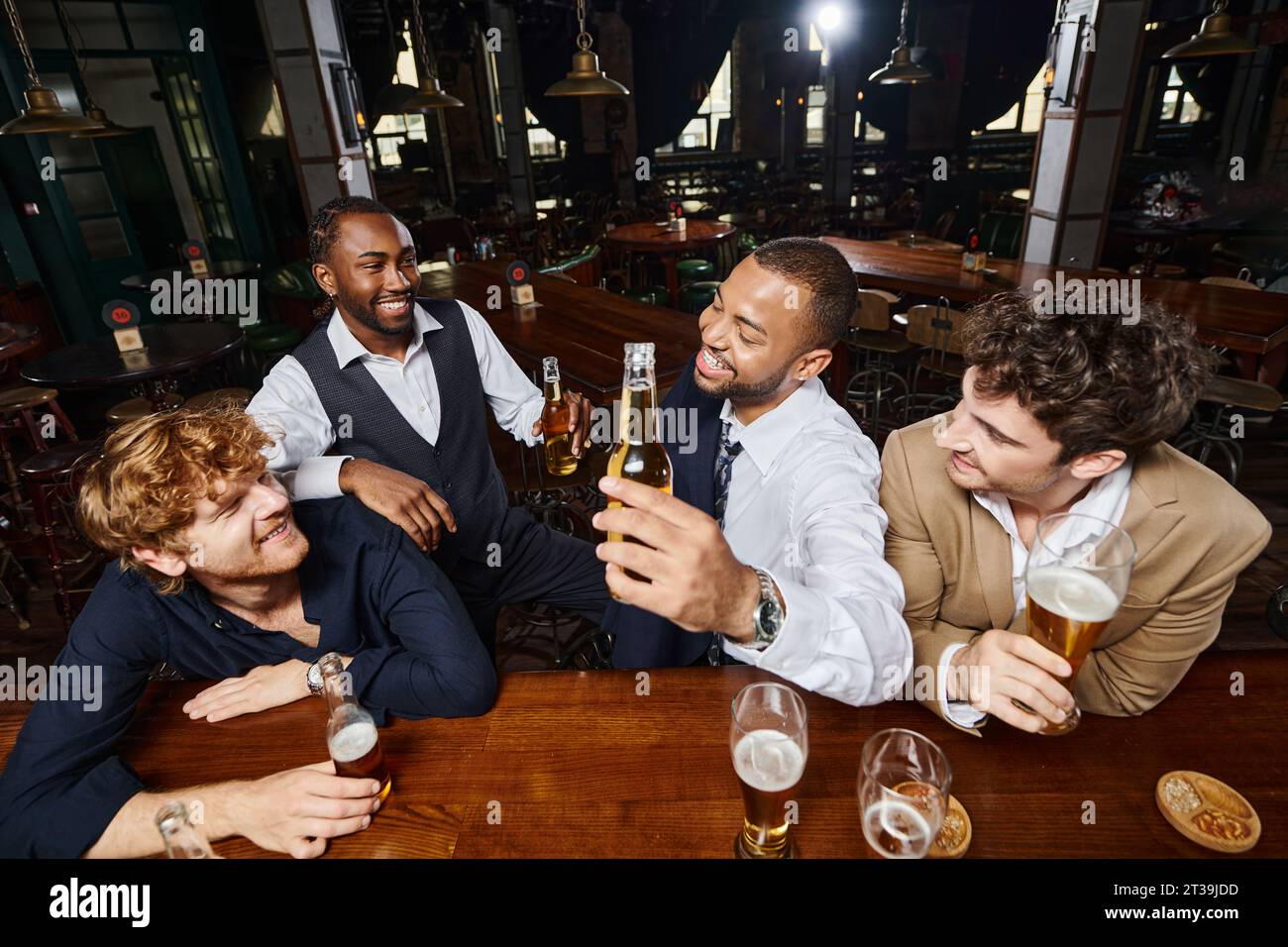 happy colleagues in formal wear chatting and drinking beer in bar ...