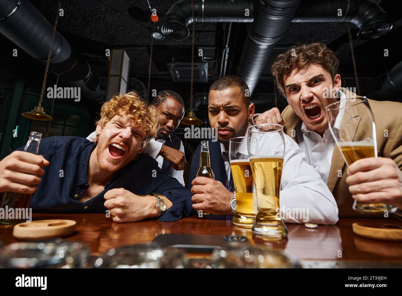 emotional multicultural colleagues in formal wear holding beer and ...