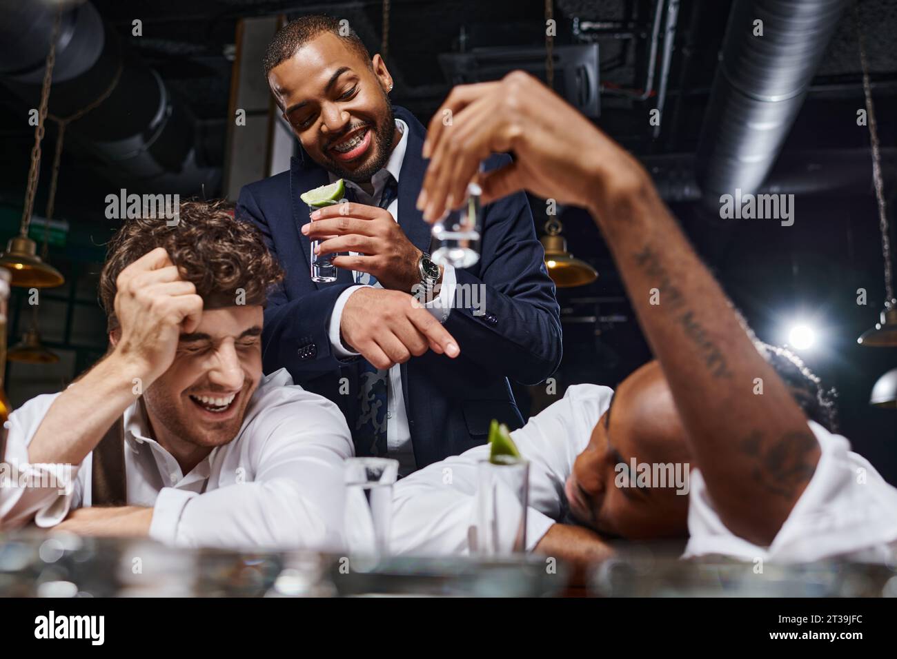 three drunk interracial friends drinking tequila shots and laughing ...