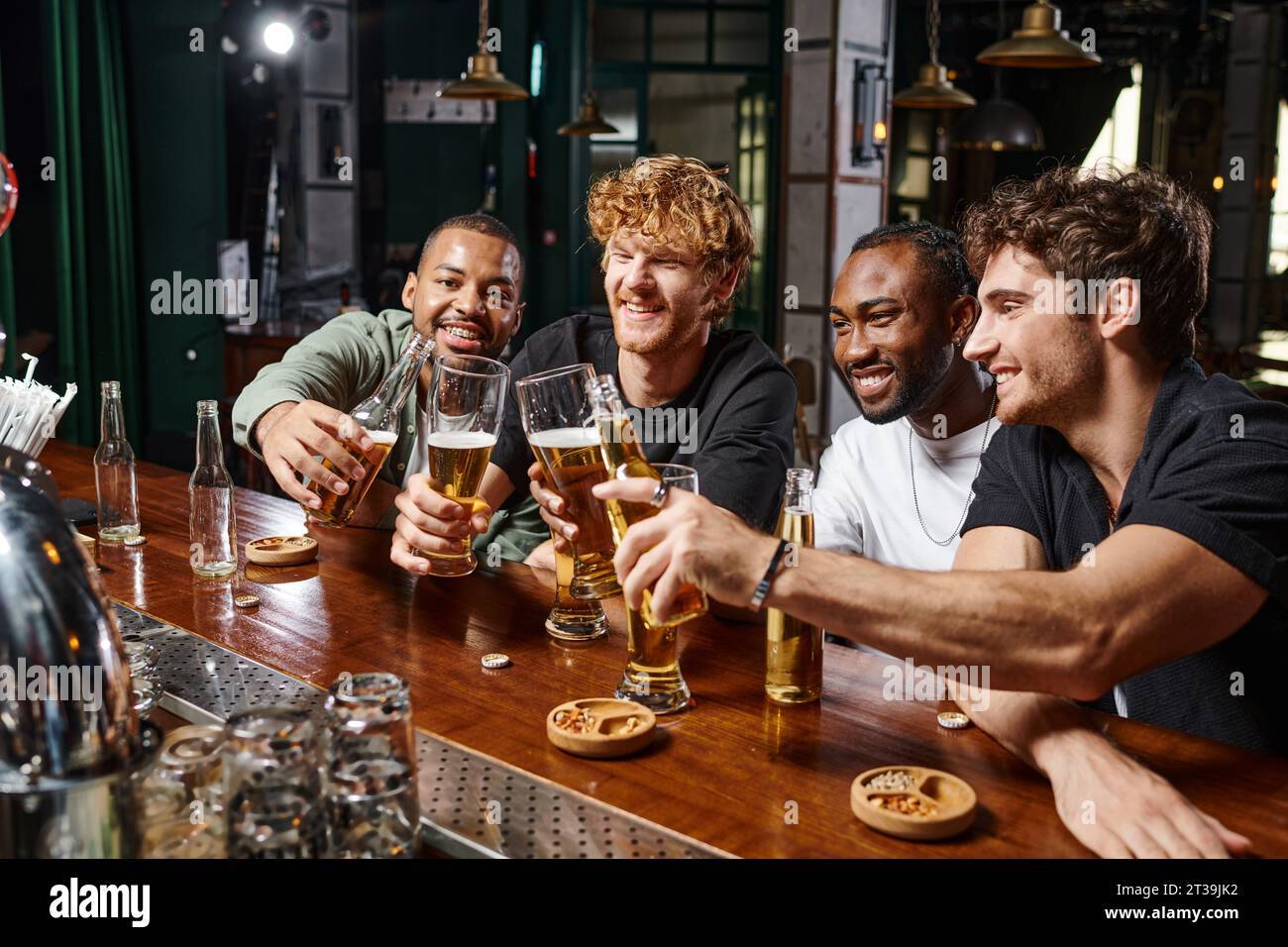group of four happy multiethnic male friends toasting with glasses of ...