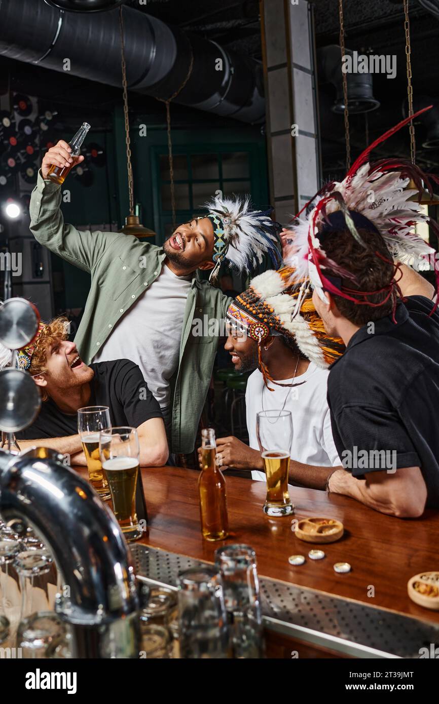 Group of young interracial men in headwear with feathers drinking beer ...