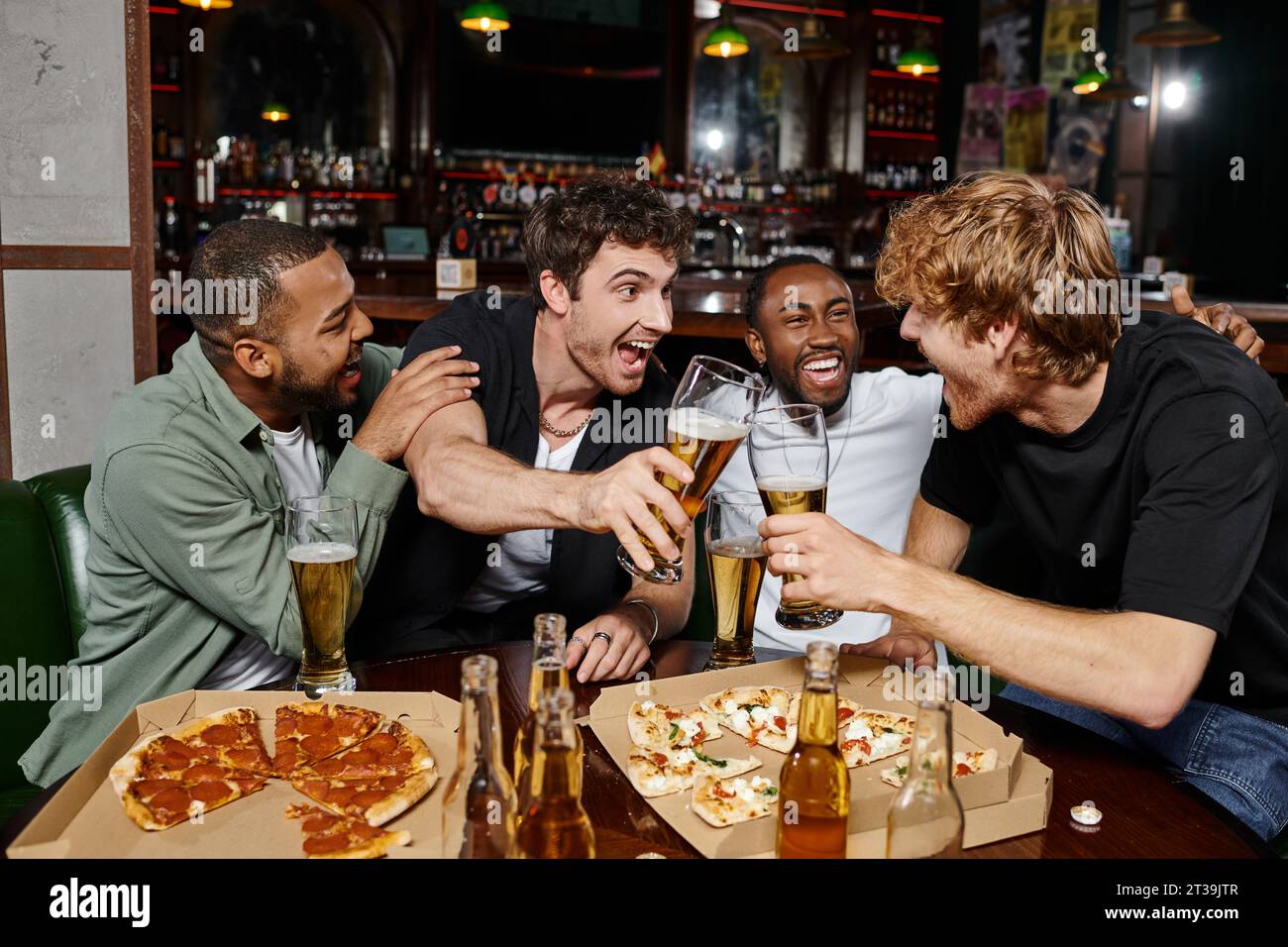 group of excited multicultural friends clinking with glasses of beer in ...