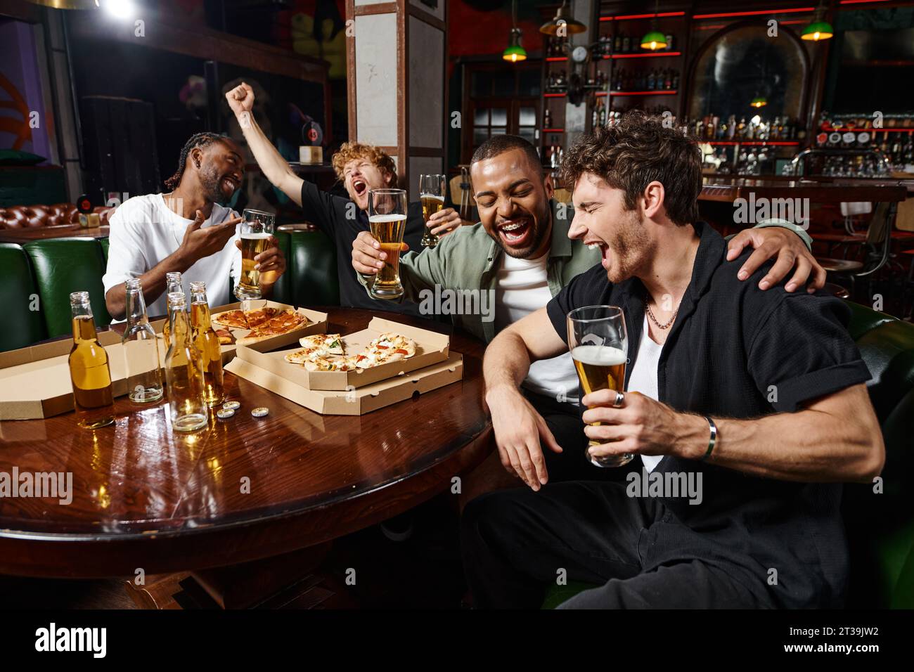 happy interracial male friends laughing and holding glasses of beer in ...