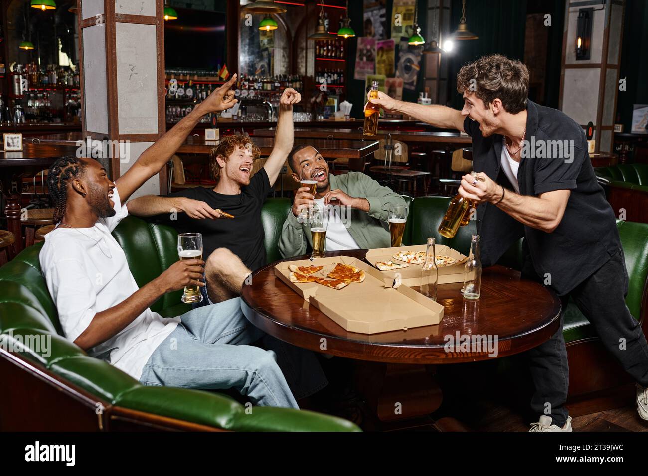four excited multicultural friends toasting with glasses of beer and ...