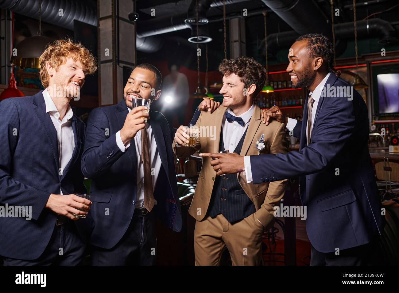 happy interracial best men in formal wear congratulating friend in bar ...