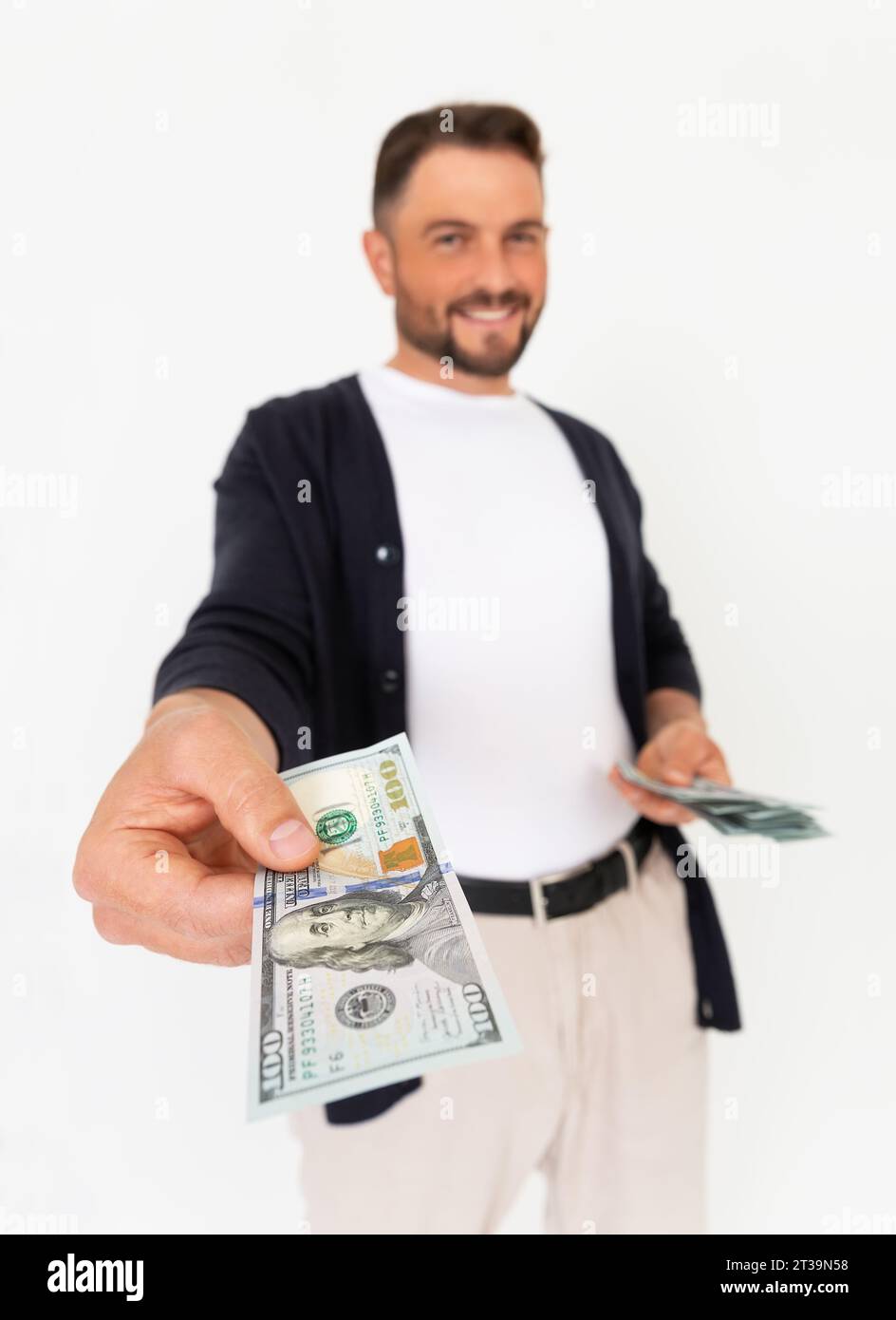 Young successful man holding out his hand with a 100 dollar bill on a ...