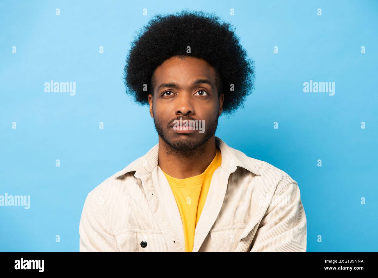 Afro African American man thinking and looking up in light blue color ...