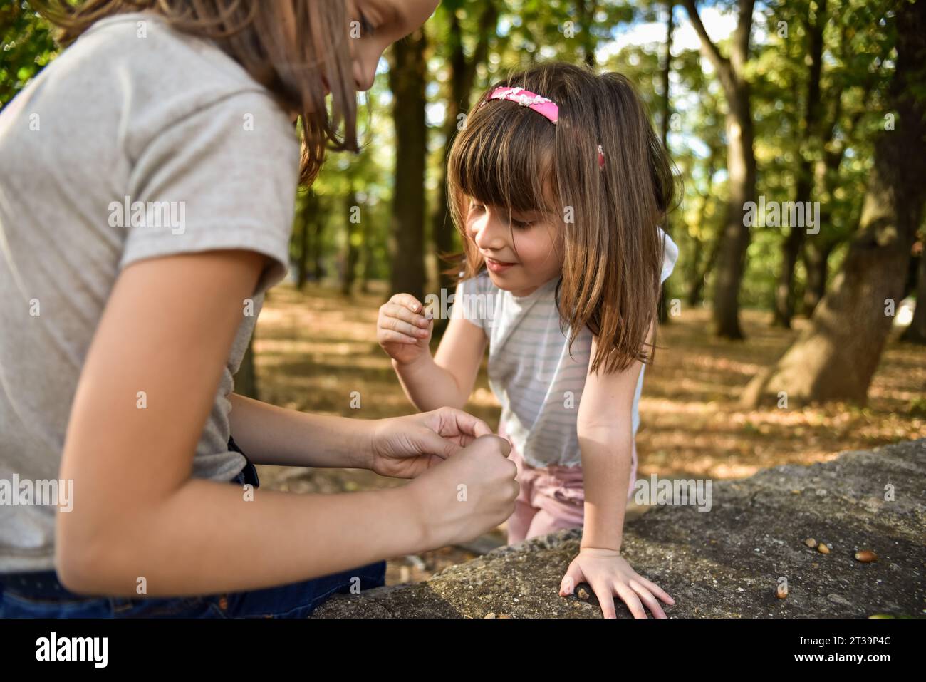 Two happy girls are playing with oak nut in the park during autumn day ...