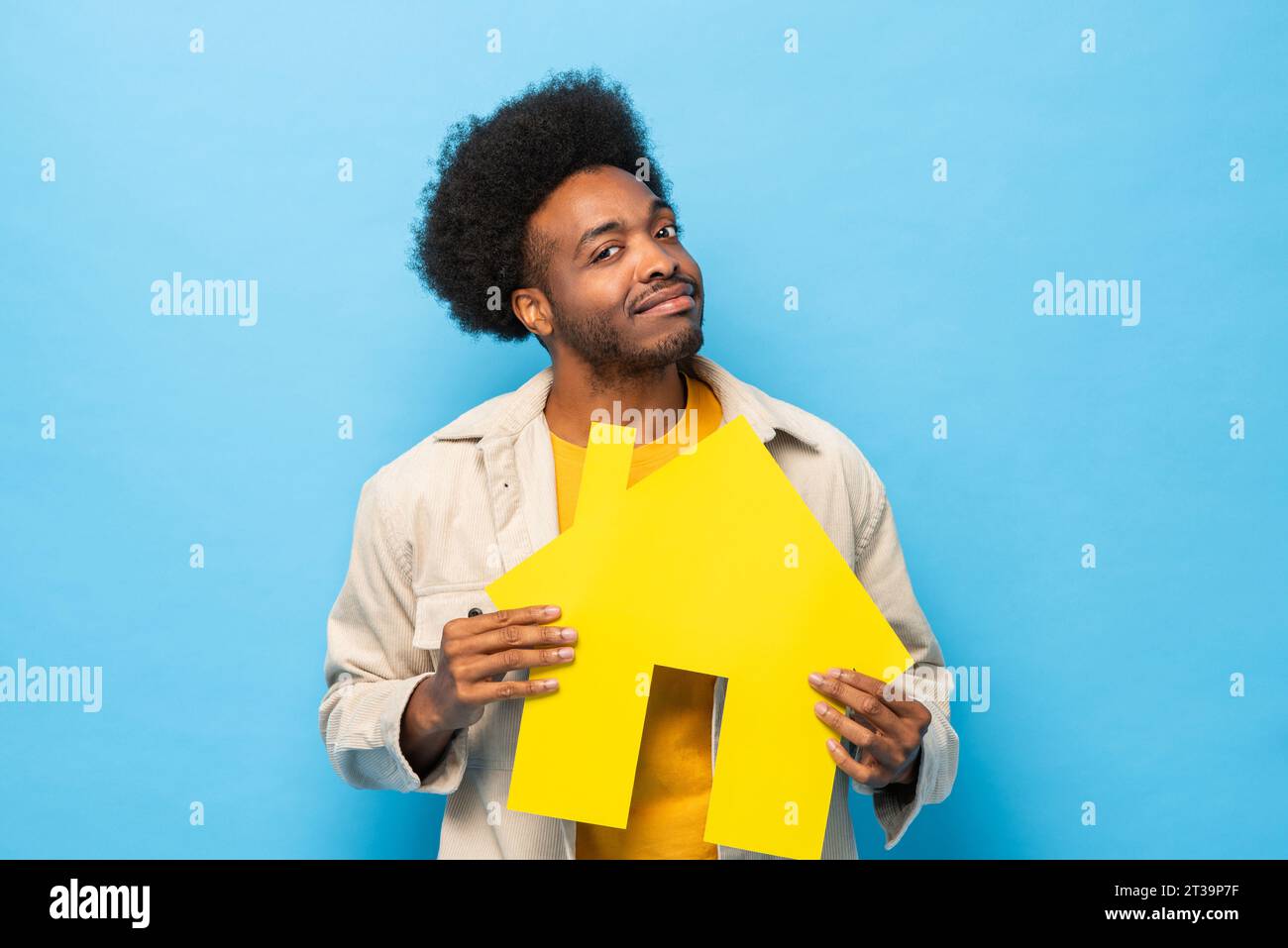 Happy smiling Afro African-American man holding house cut out in ...