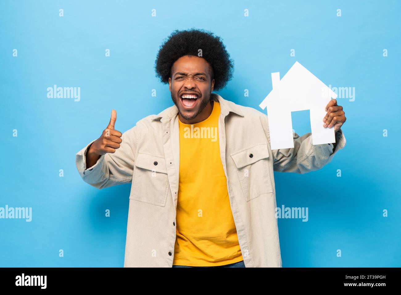Happy smiling Afro African-American man holding house cut out in ...