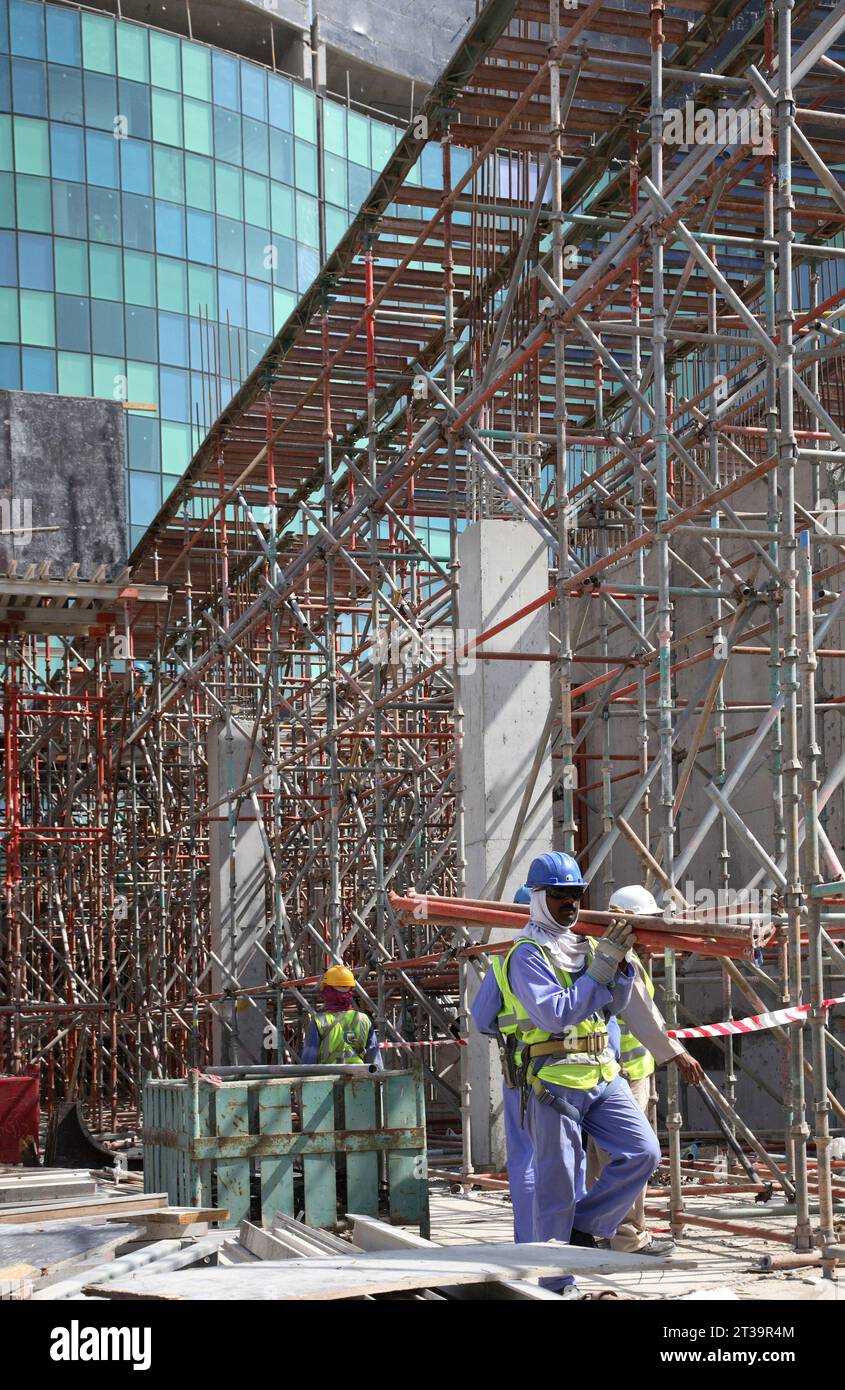 Foreign workers from India and Pakistan assemble scaffolding on a large ...
