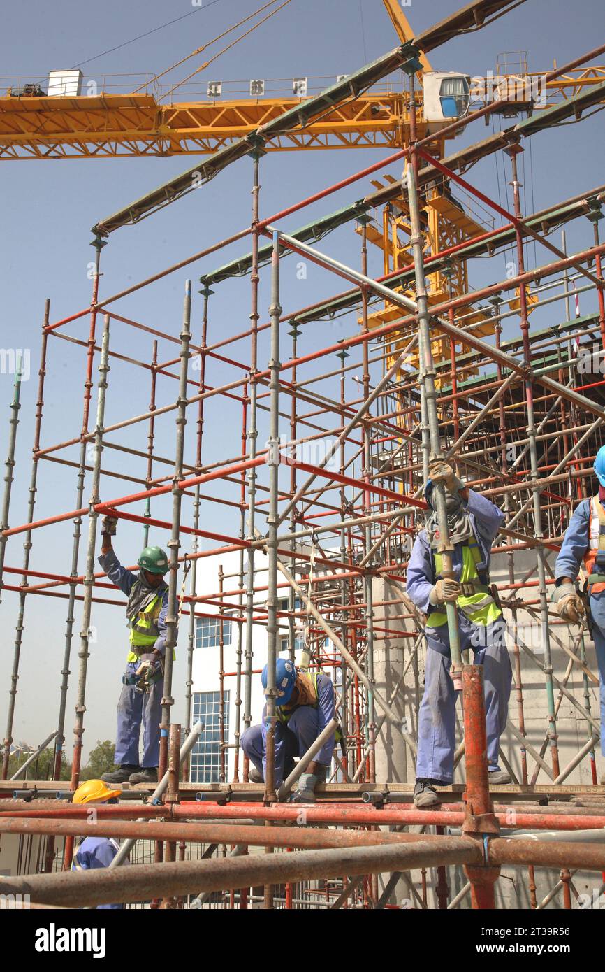 Foreign workers from India and Pakistan assemble scaffolding on a large ...