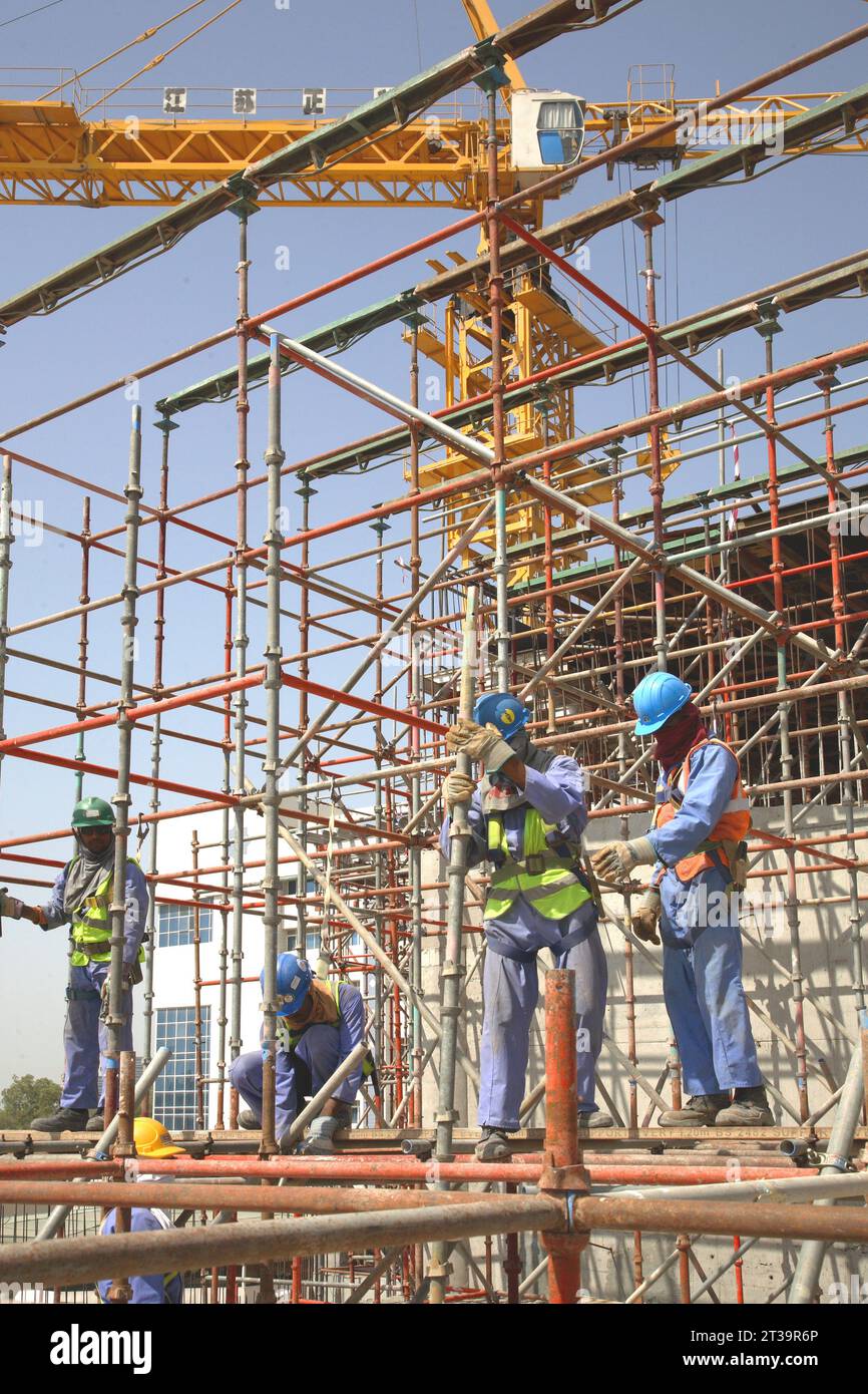 Foreign workers from India and Pakistan assemble scaffolding on a large construction site in Abu ...