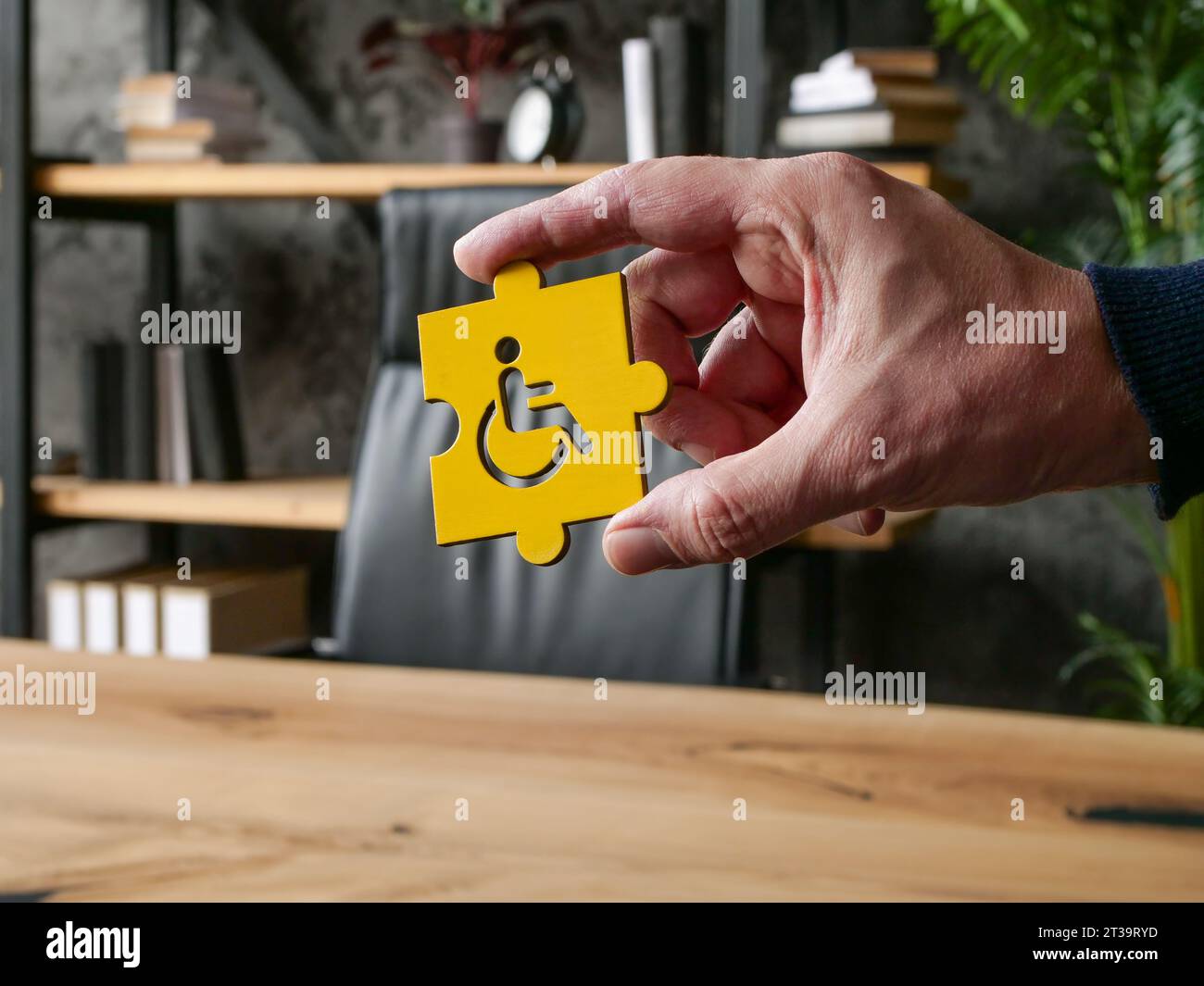 A hand holds puzzle disabled person symbol in the workplace as a symbol ...