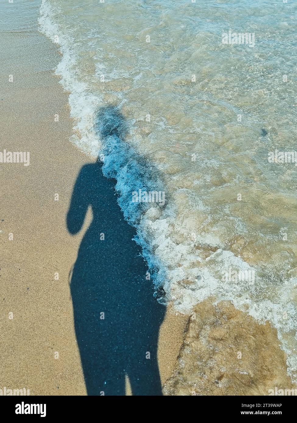 female shadow on the beach. golden sand and blue waves of the sea ...