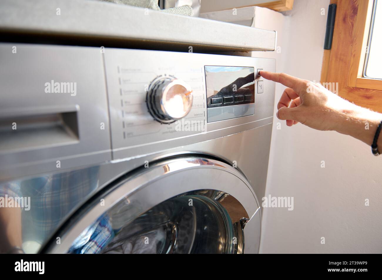 Close-up male hand switching on, turning on automatic washing machine ...