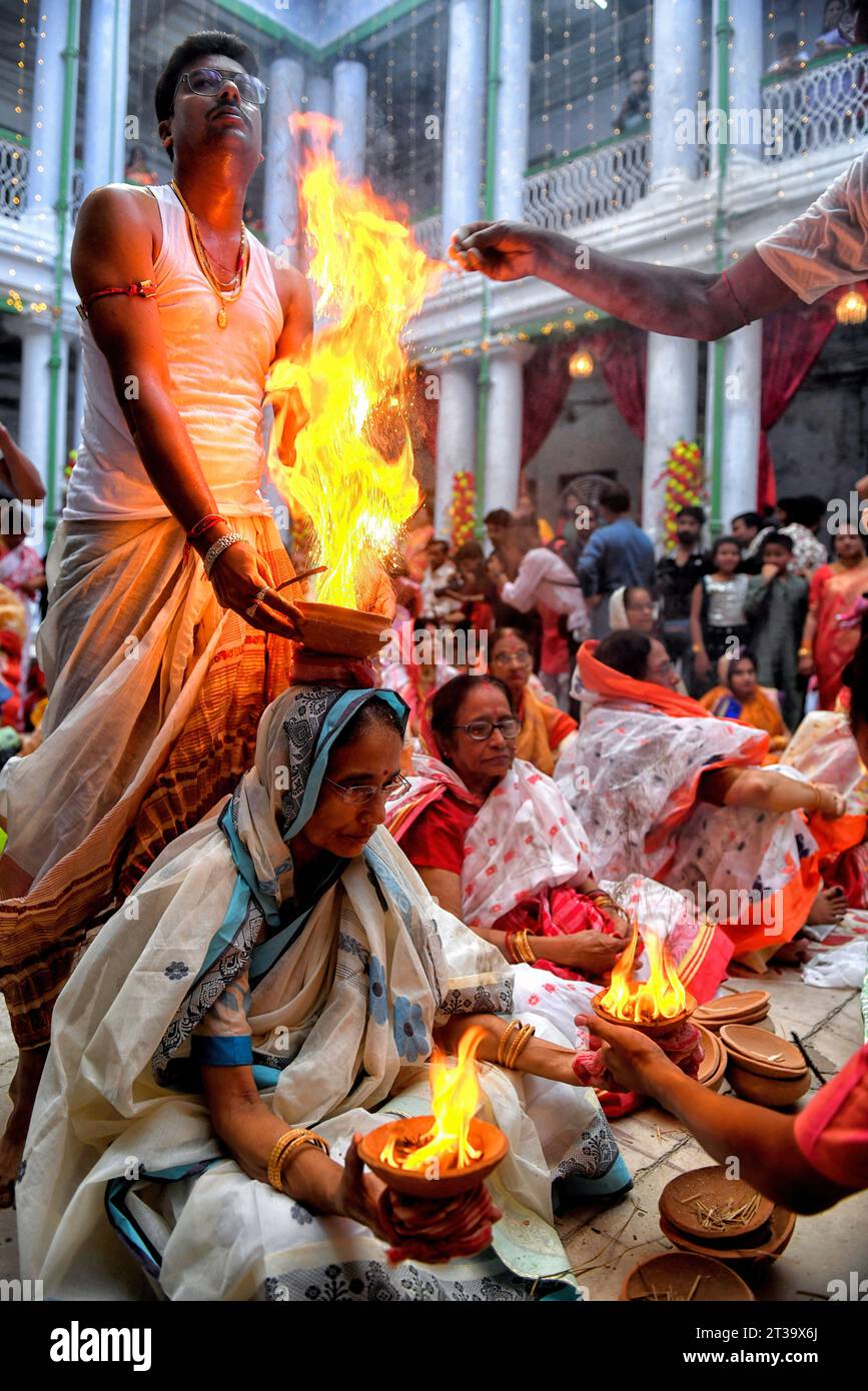 Kolkata, India. 22nd Oct, 2023. An Indian Hindu woman sits with burning ...