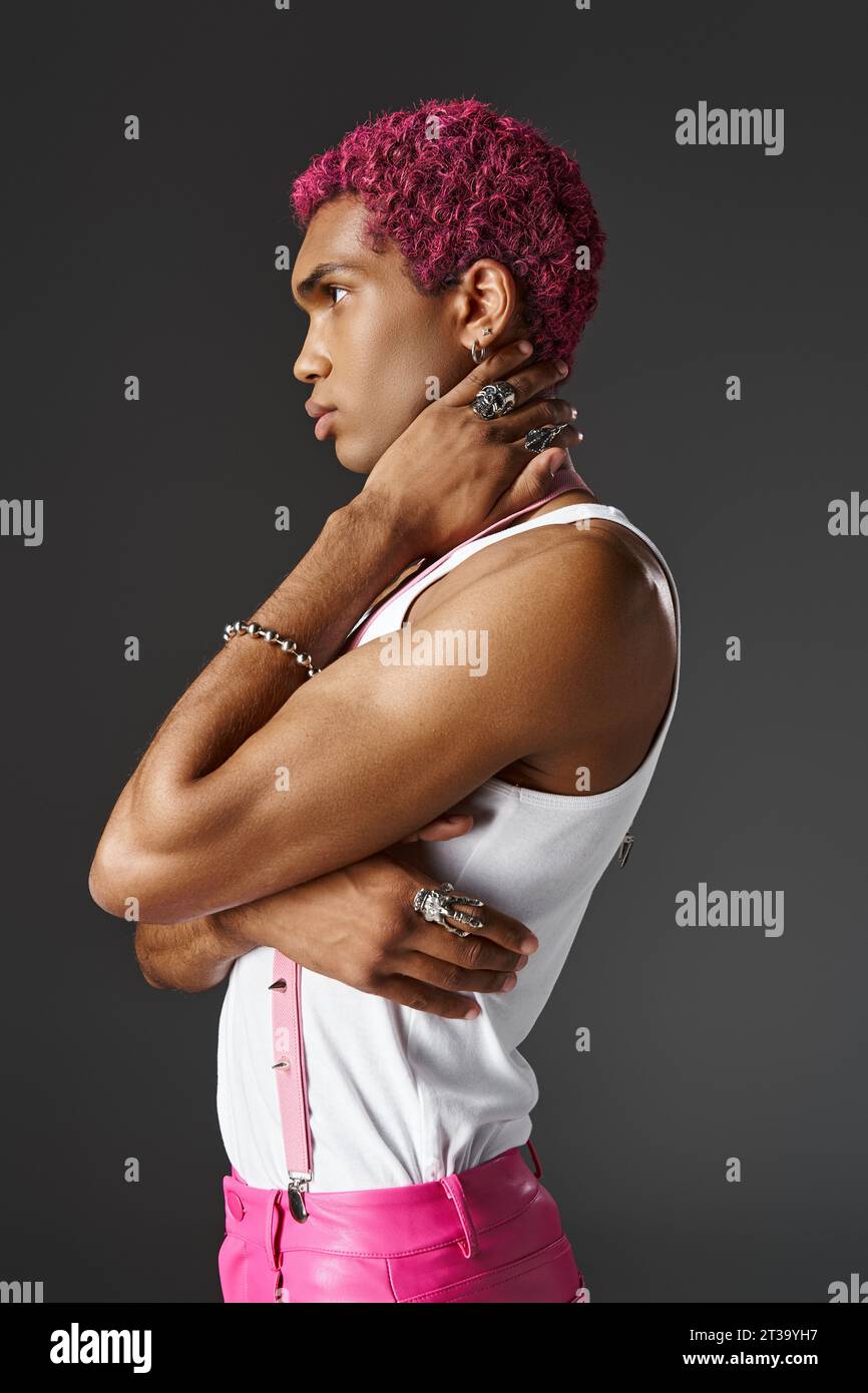 serious good looking man with crossed arms and hand behind neck on gray ...