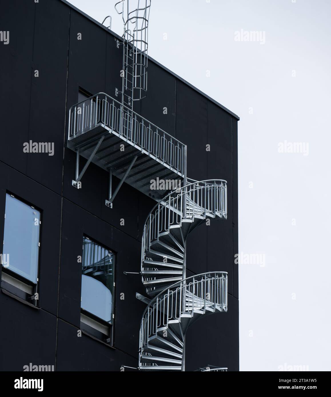 Spiral external emergency stairs by a black building Stock Photo - Alamy