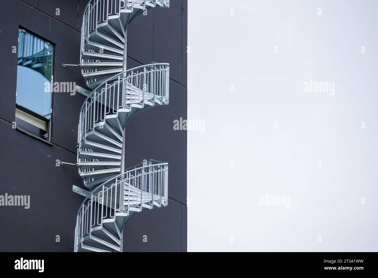 Spiral external emergency stairs by a black building Stock Photo - Alamy