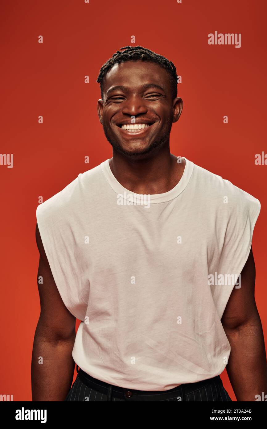 happy and sporty african american man in white tank top smiling at ...