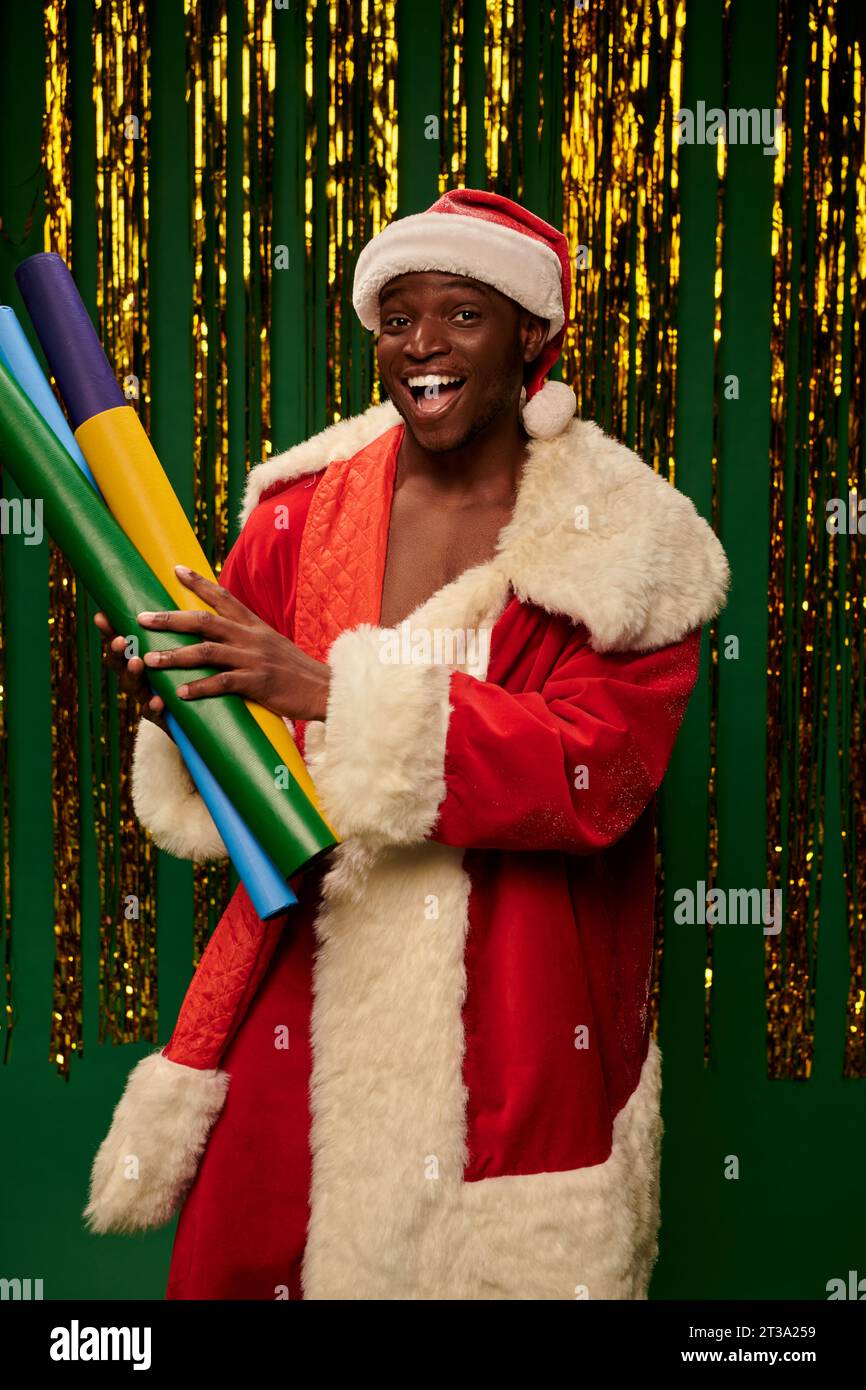 excited african american man in santa costume with colorful wallpapers ...