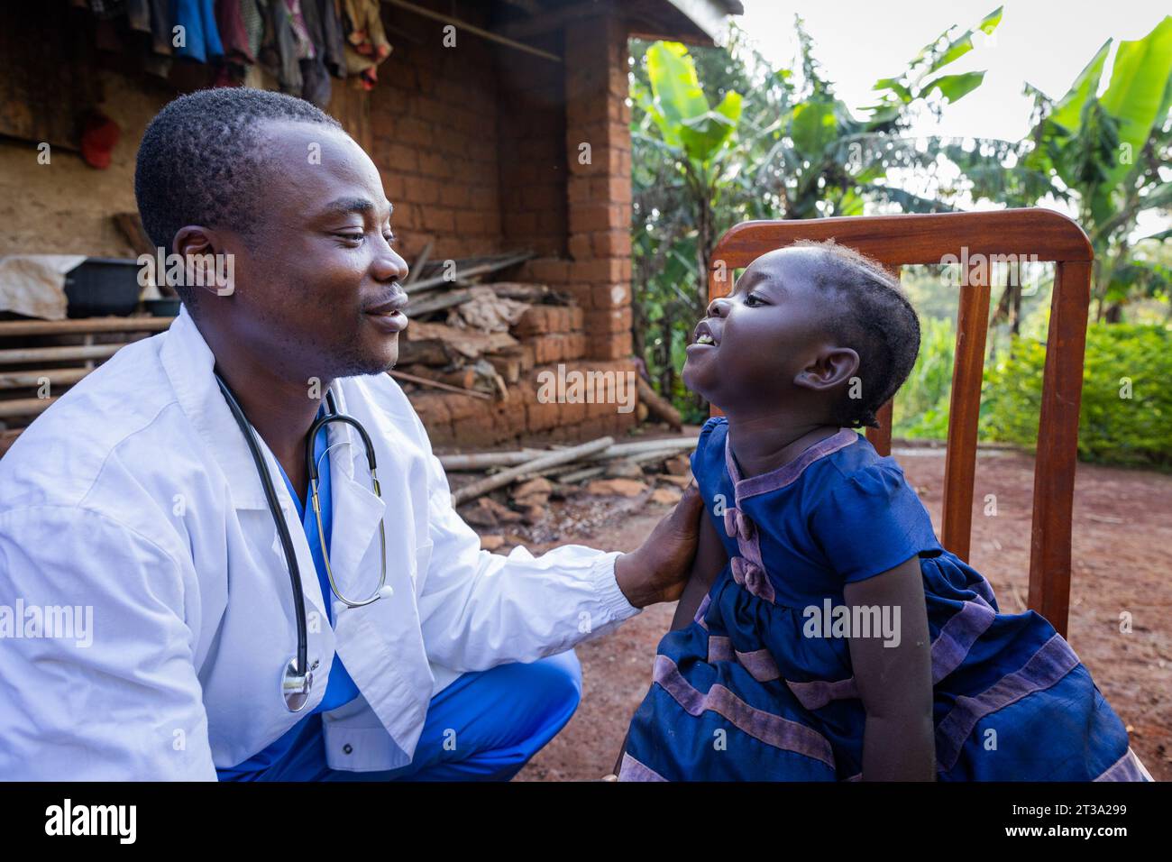 African doctor talking to a sick baby girl during a visit in a rural ...