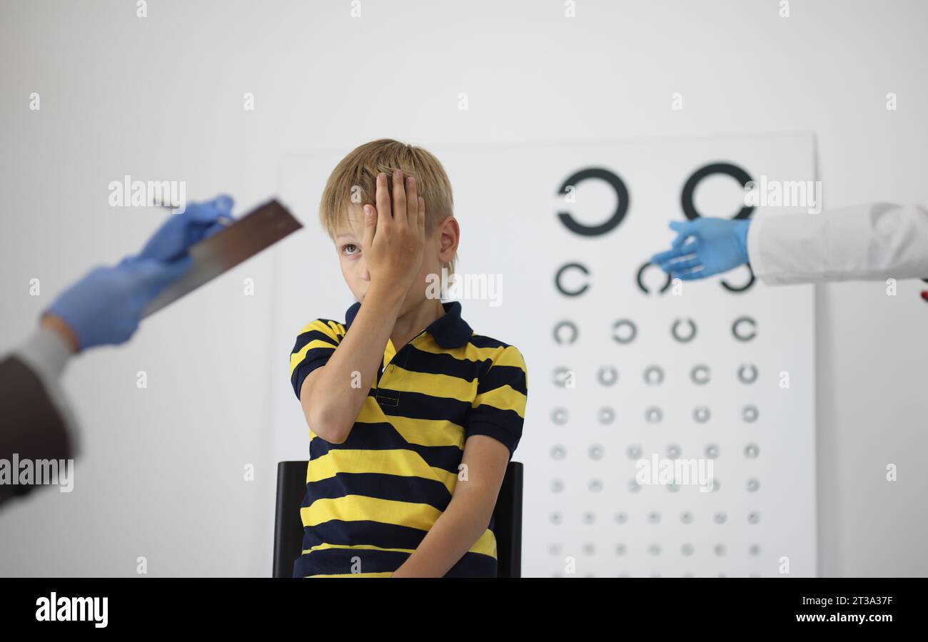 Boy at an ophthalmologist's appointment closes one eye and answers ...