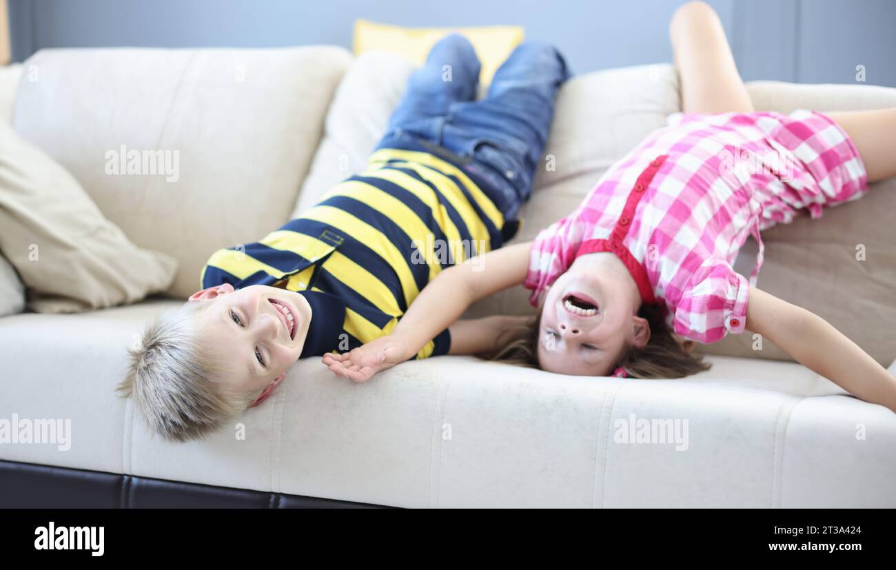 Boy and a girl lie upside down on the couch and laugh Stock Photo - Alamy