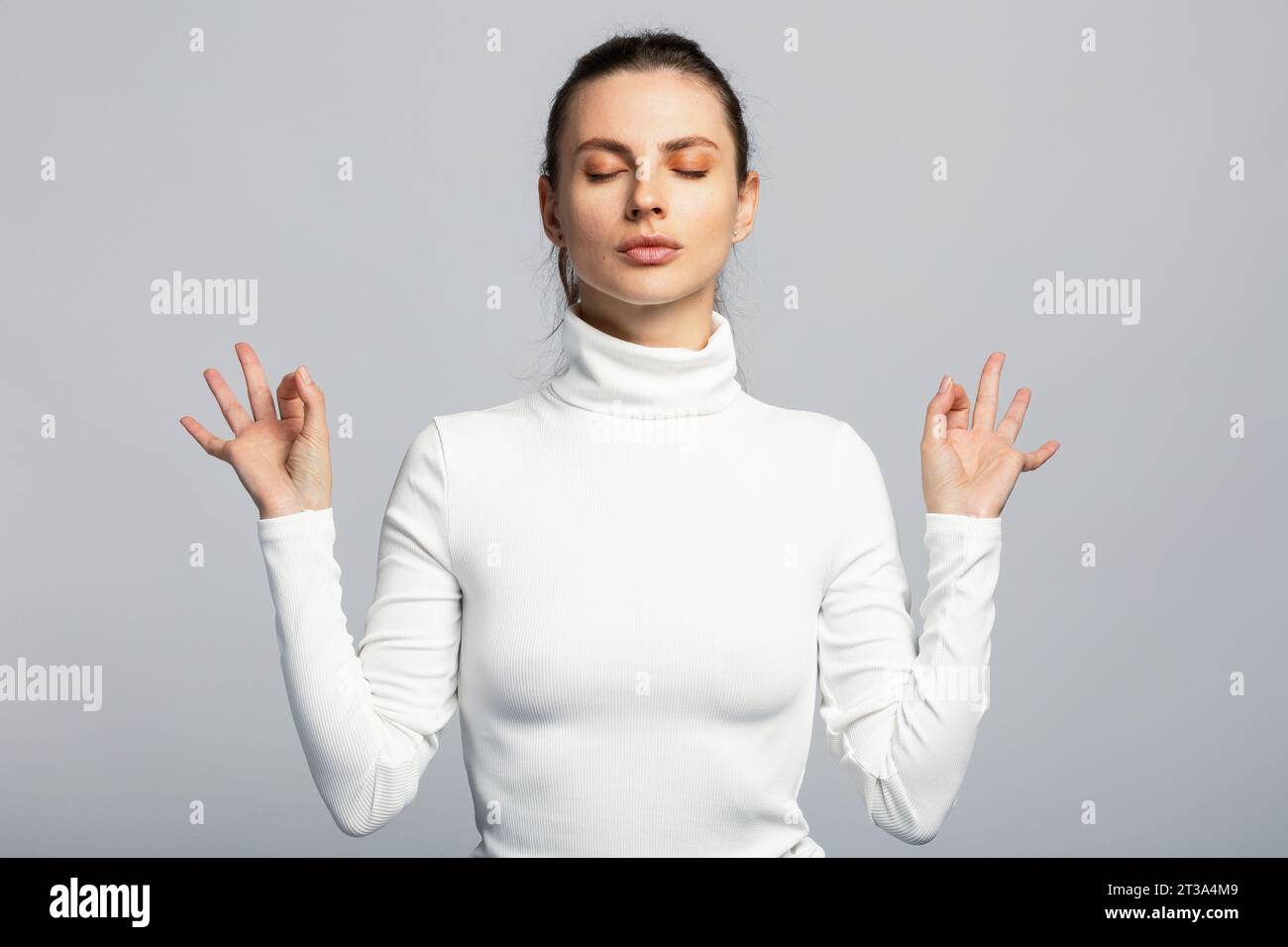 Young female beauty meditating and making zen gesture with her fingers ...