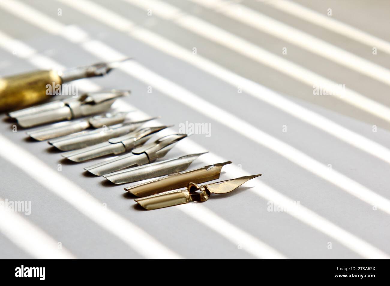 metal tips for the ink pen on a white background in solar rays ...