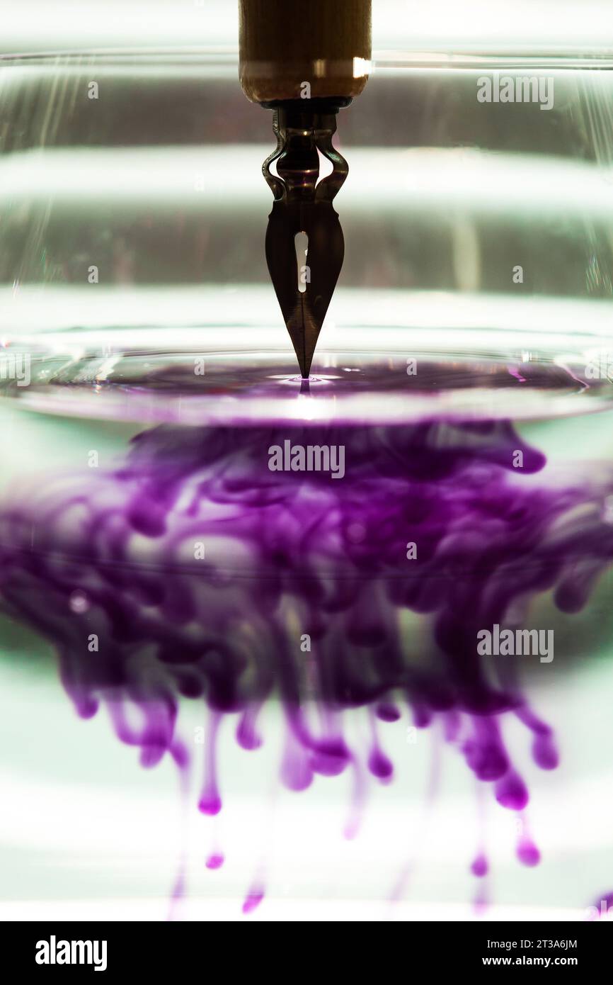 metal tip of ink pen dipped in water. diffusion of blue ink in a ...