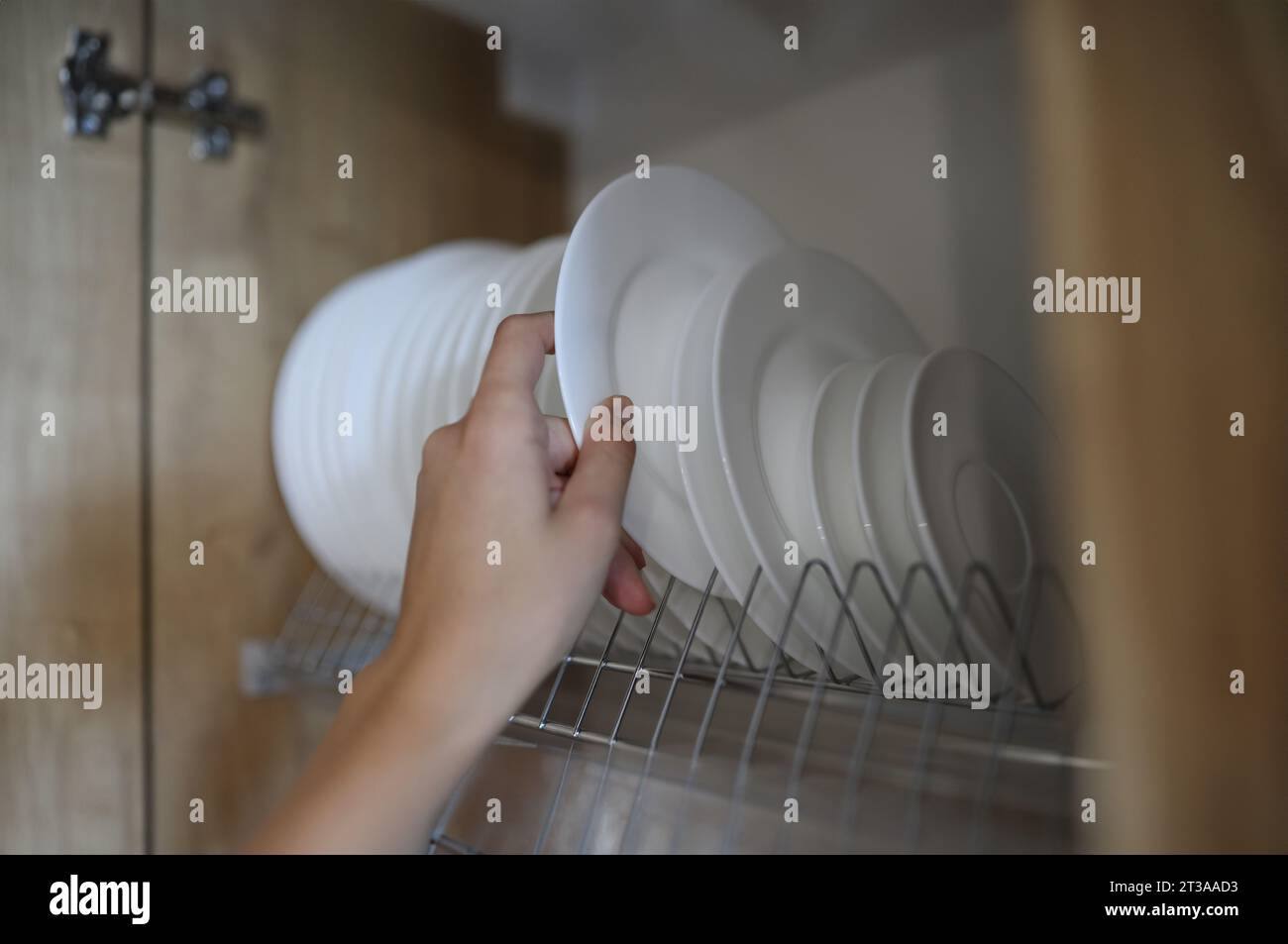 Woman's hand pulls clean white dishes out of kitchen cabinet Stock ...