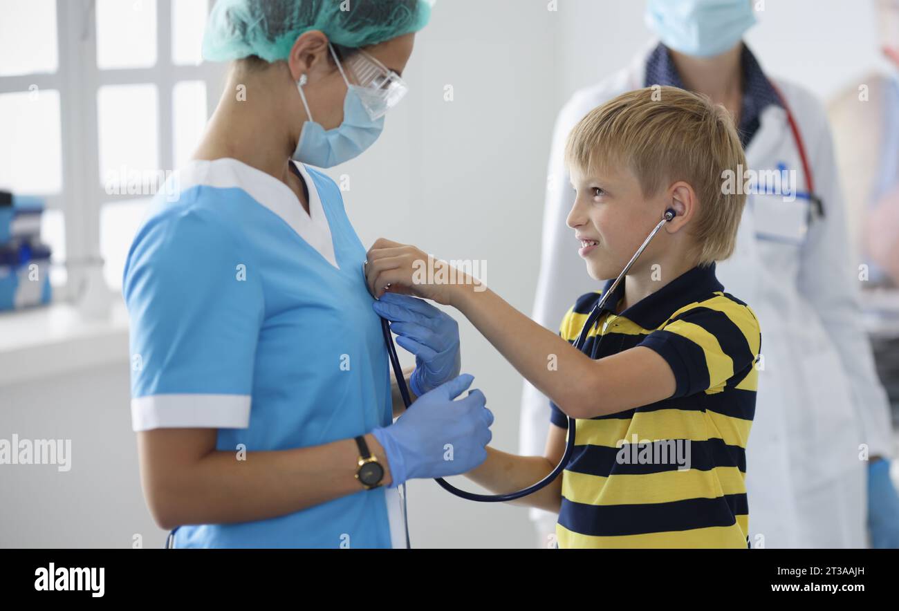 Boy in medical office listens to doctor's breath through stethoscope ...