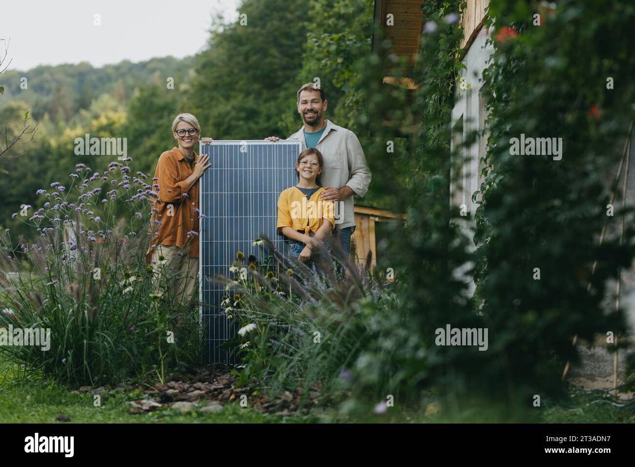 Father mother and daughter standing in garden with solar panel. Solar ...