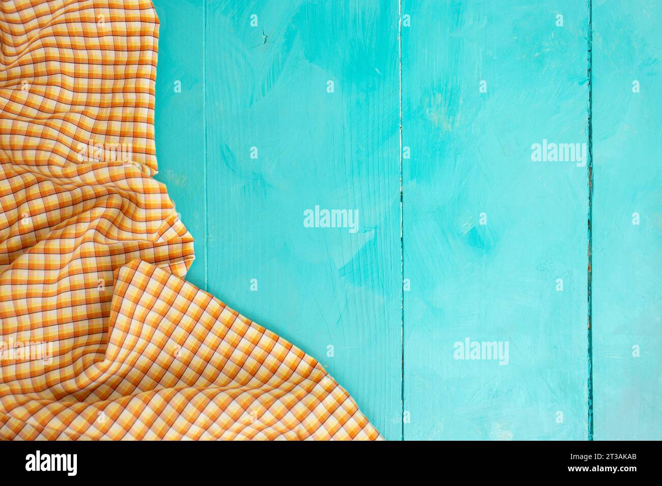 Orange checkered cloth on wooden blue boards table background, copy ...