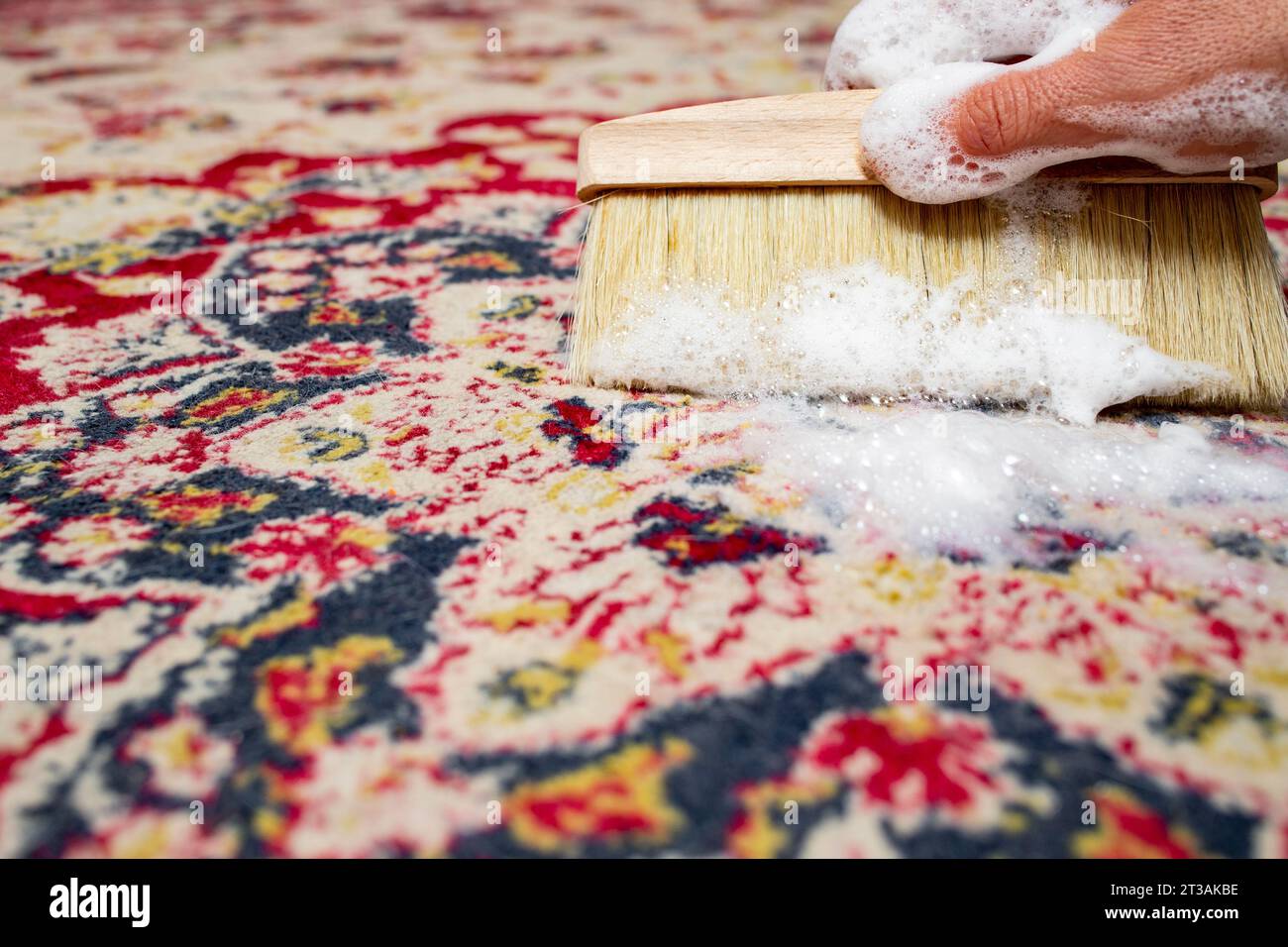 Male holding a brushing a natural fiber rug with white foam, abstract ...