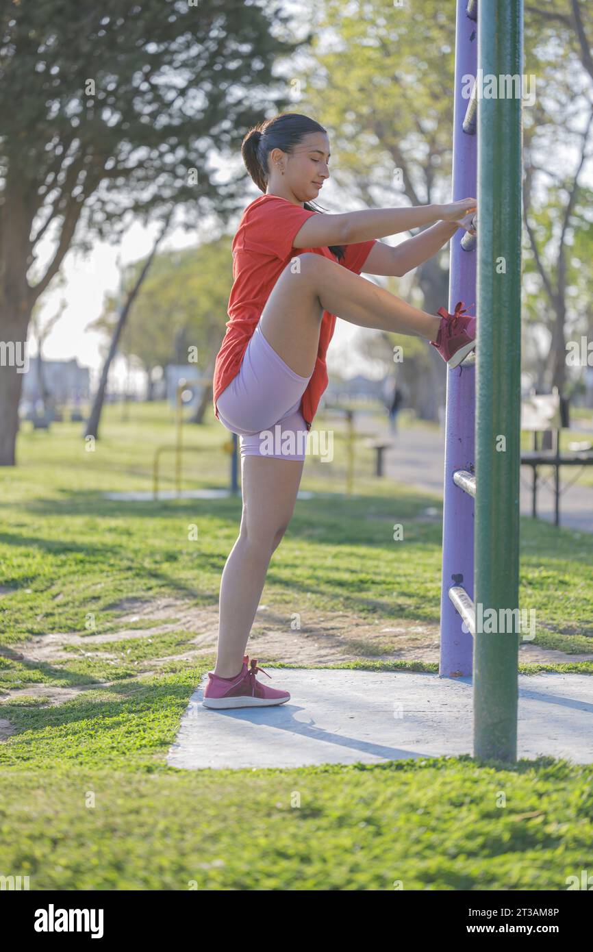 Latin girl doing leg stretches in a public park Stock Photo - Alamy