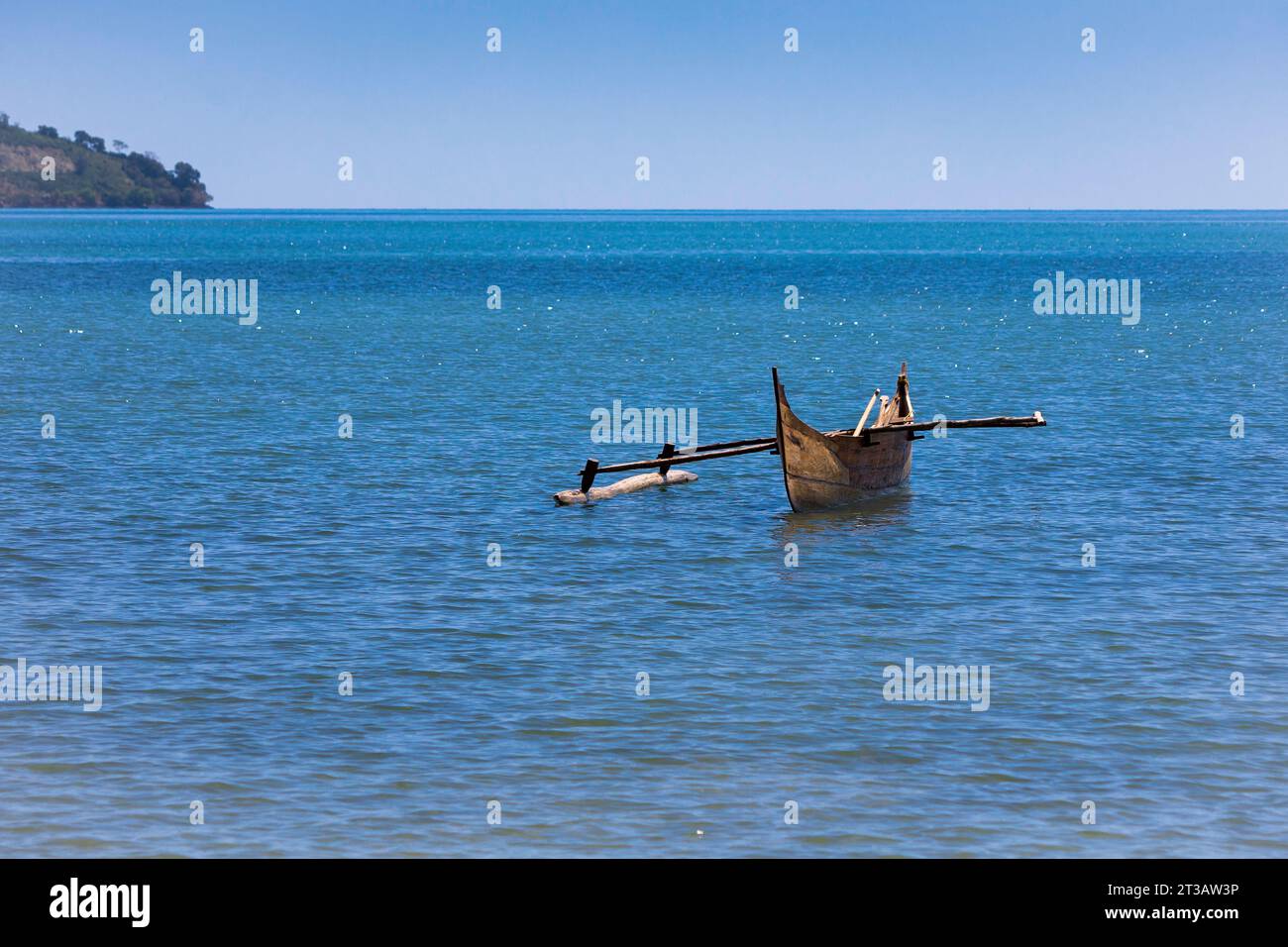 A dugout canoe drifting in the shallow water off an island with blue ...
