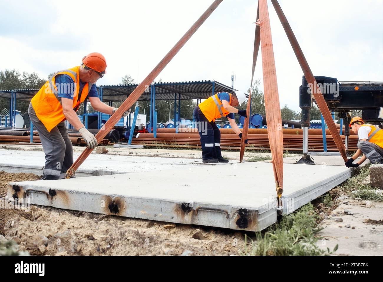 Builders in hard hats work on construction site. Team of workers lays ...