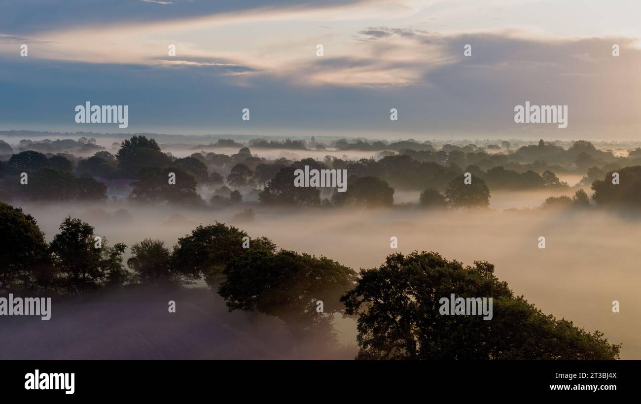 Early morning mist or fog creeping across the fields and woods near ...