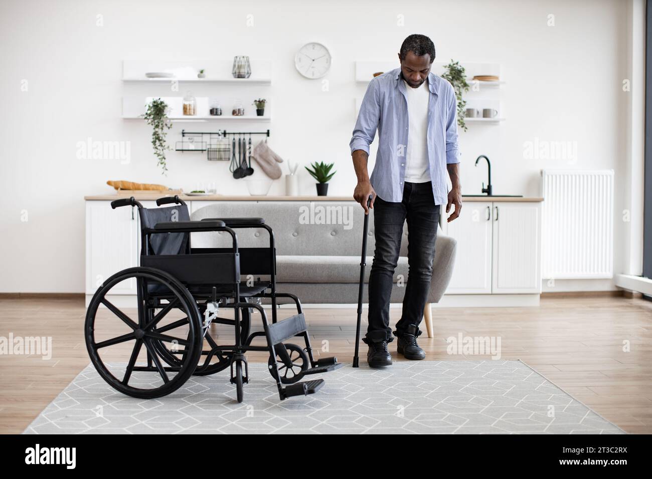African man with disability using walking stick when raising from ...