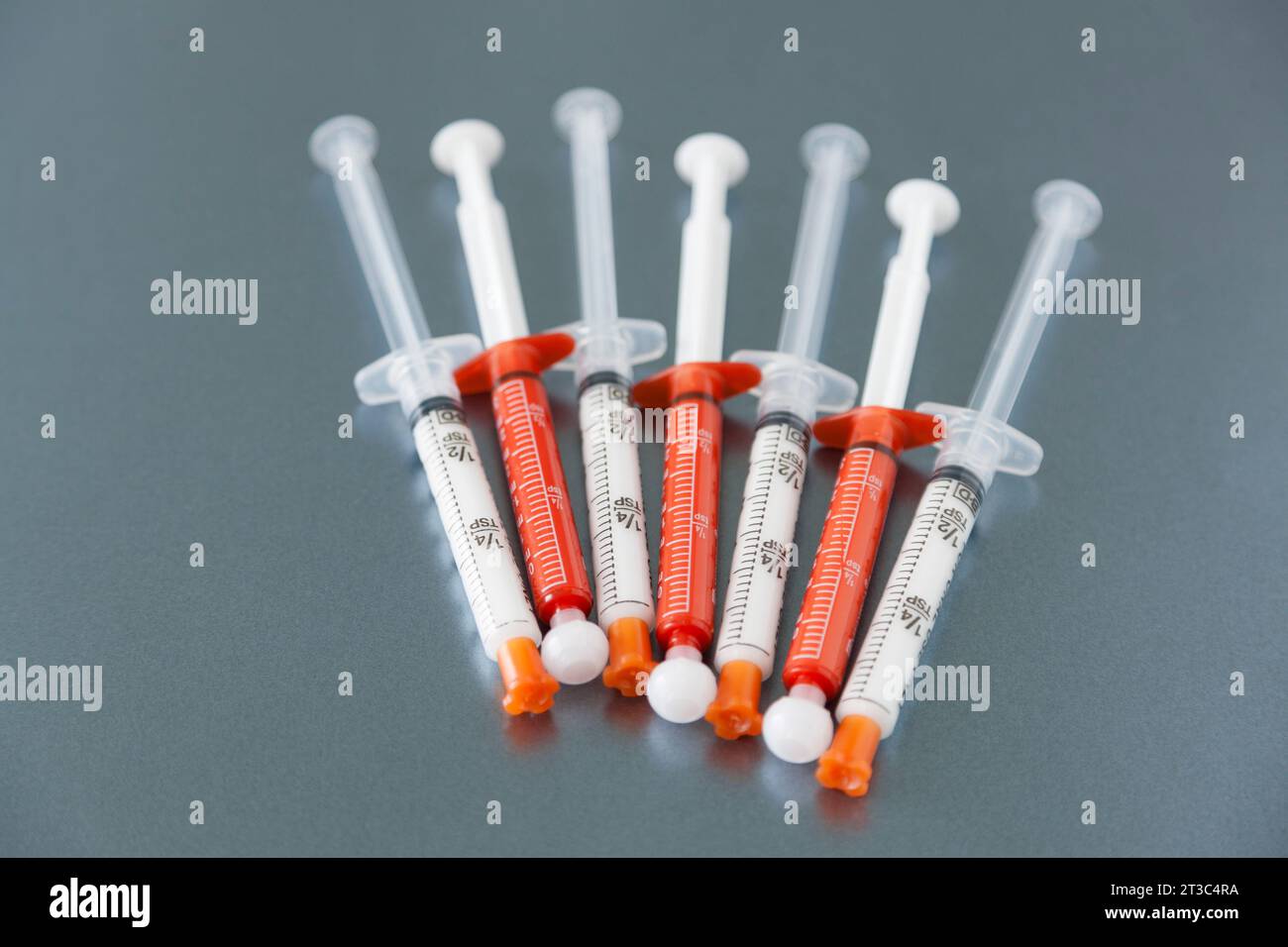 7 syringes in a row on grey background Stock Photo - Alamy