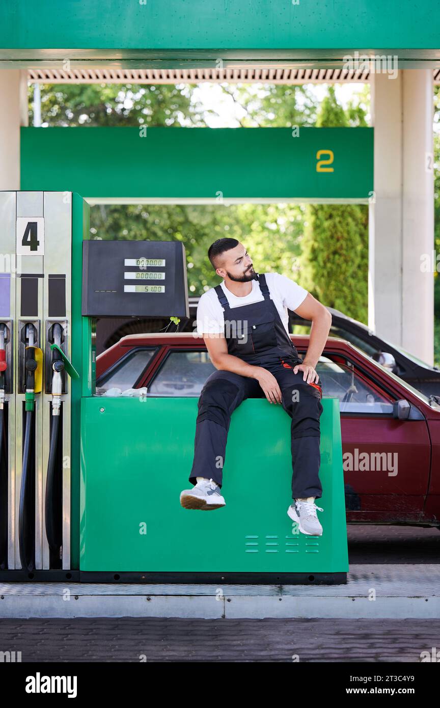 Young gas station operator waiting for new customers. Professional ...