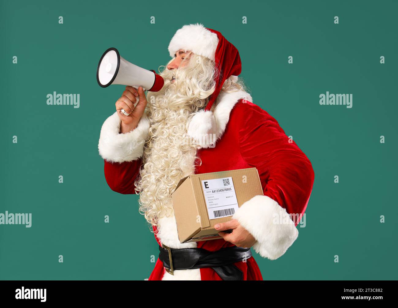 Santa Claus with megaphone and parcel on green background Stock Photo ...